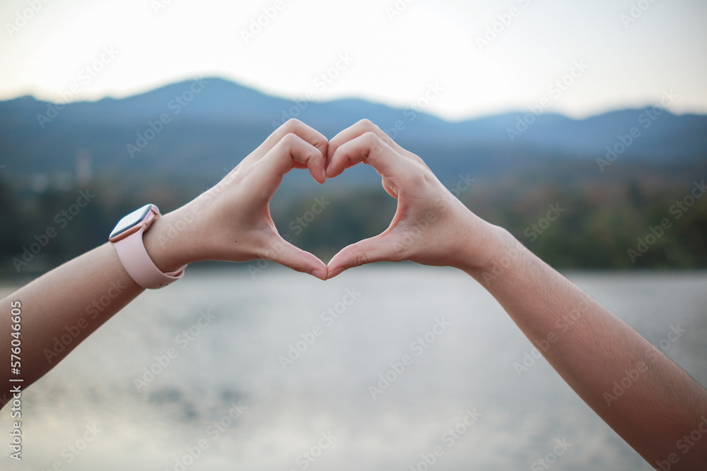 male and female couple showing their hands up to form heart symbol to ...