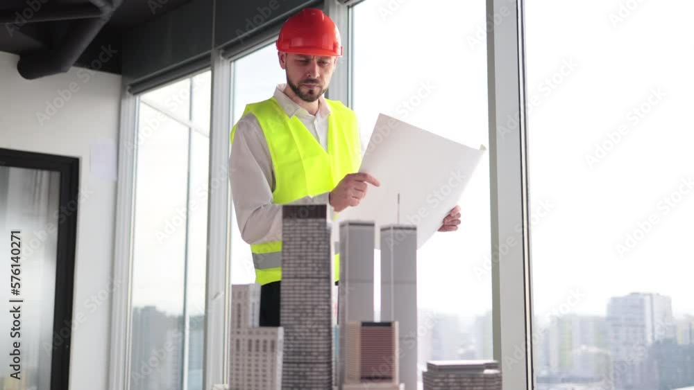 Engineer man in helmet and reflective vest holding blueprint standing ...