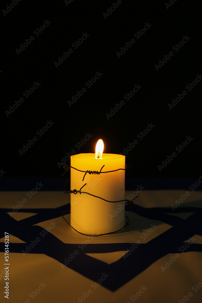Burning candle with barbed wire on flag of Israel against dark ...