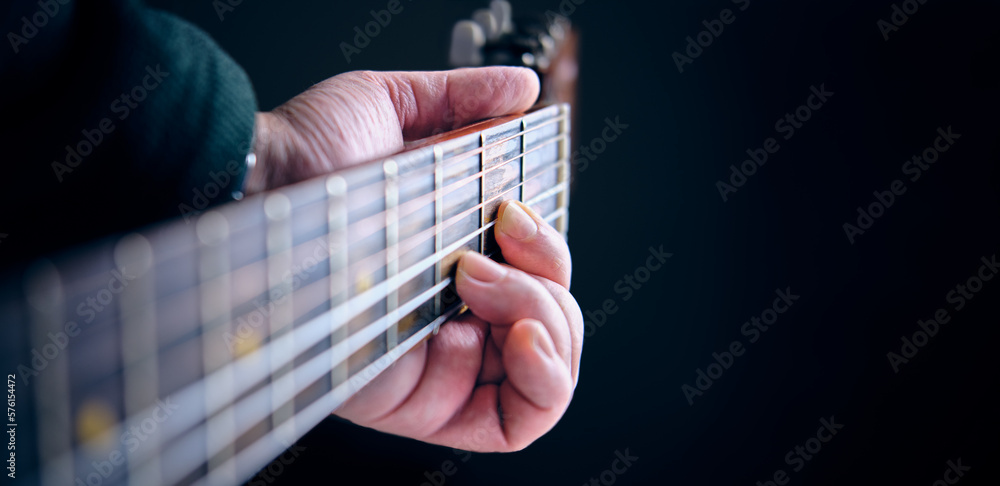 Man's hand playing a six string acoustic guitar with a worn out ...