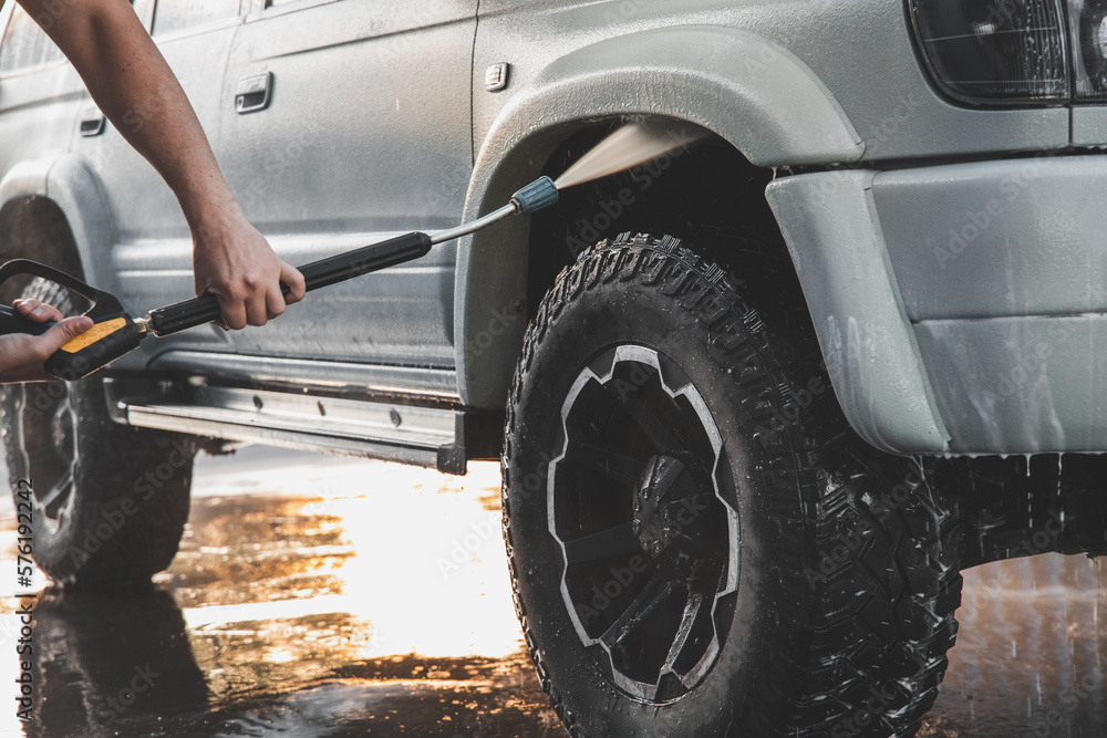 Man washes his offroader car at a self-service car wash with a high ...