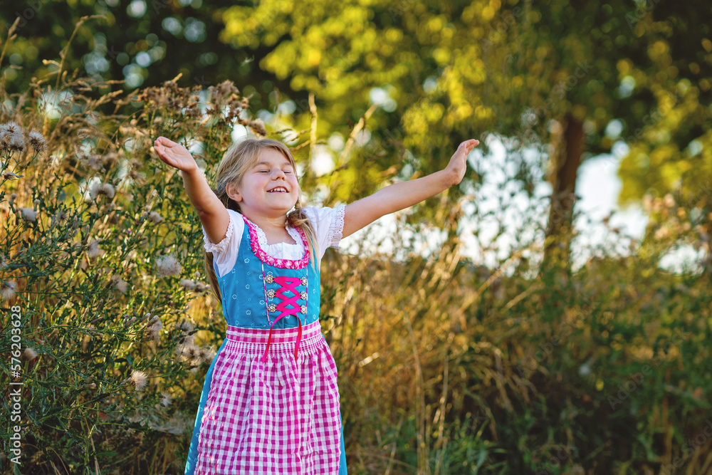 Cute little kid girl in traditional Bavarian costume in wheat field ...