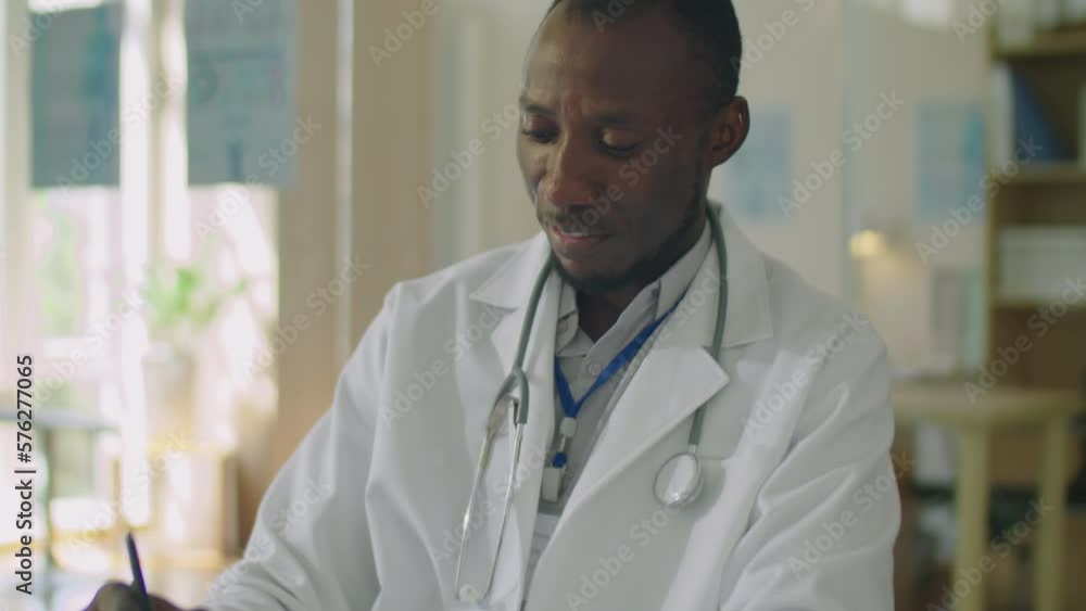 African American male doctor taking notes and speaking with patient ...
