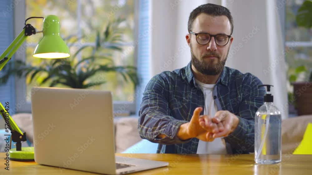 Man sit down at workplace and disinfect hands in home office. Realtime ...