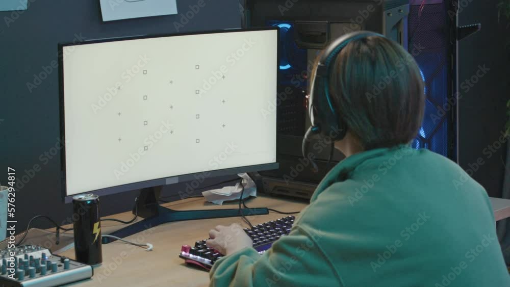 Medium rear shot of unrecognisable young male or female gamer sitting ...