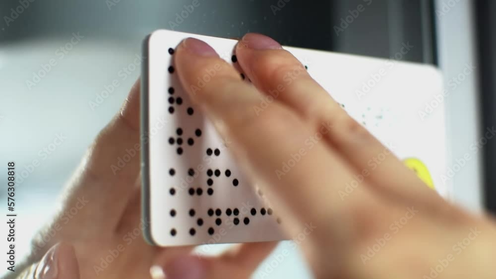 Person with blindness touches and reads with his hands the Braille text ...