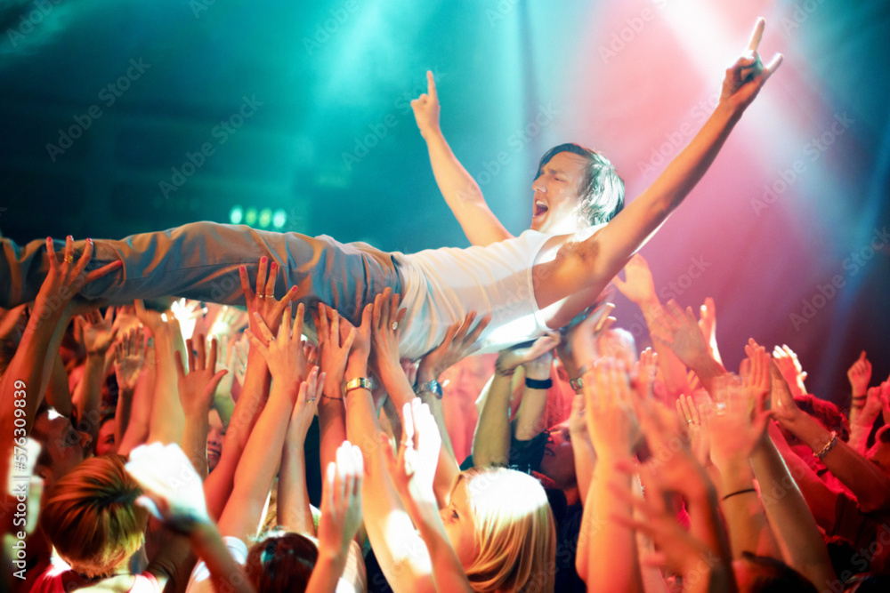 A young man cheering as he crowd surfs at a concert. This concert was ...
