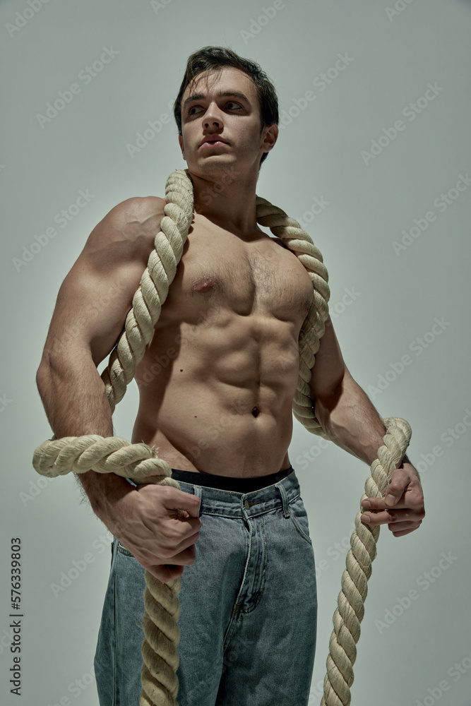 Handsome young man with strong muscular body shape posing in jeans with ...