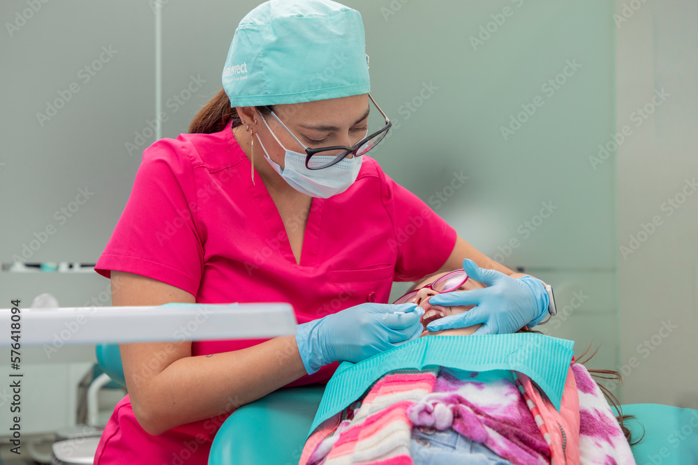 Female dentist applying fluoride to a girl in her dental office Stock ...
