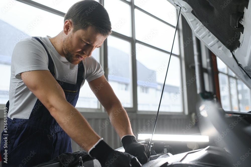 Handsome young male auto mechanic in special uniform clothes holding a ...