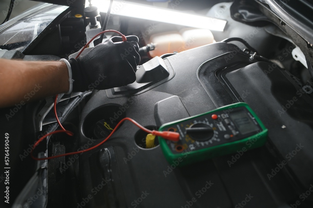 Car mechanic is using a multimeter with voltage range measurement to ...