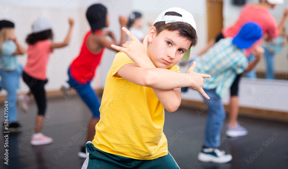 Portrait of cheerful preteen girl practicing dance movements with group ...