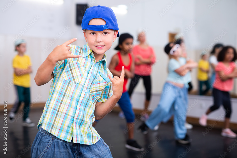 Portrait of cheerful preteen girl practicing dance movements with group ...