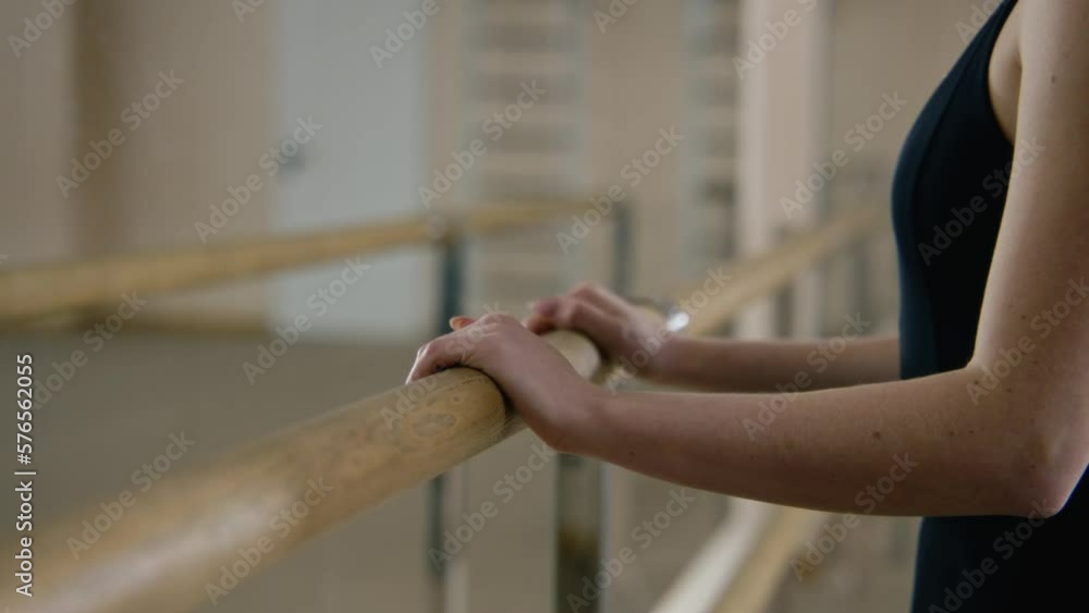 Ballerina in training bodysuit stands near ballet barre in dance studio ...