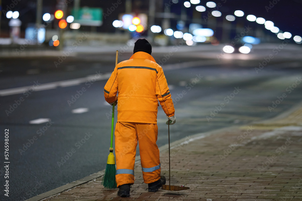 Utility worker with broomstick and scoop for garbage work at night ...