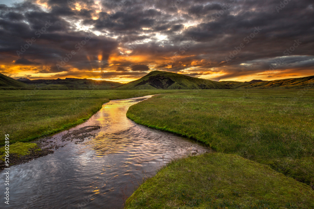 Landmannalauger Highlands stream through mossy field and sun rays ...