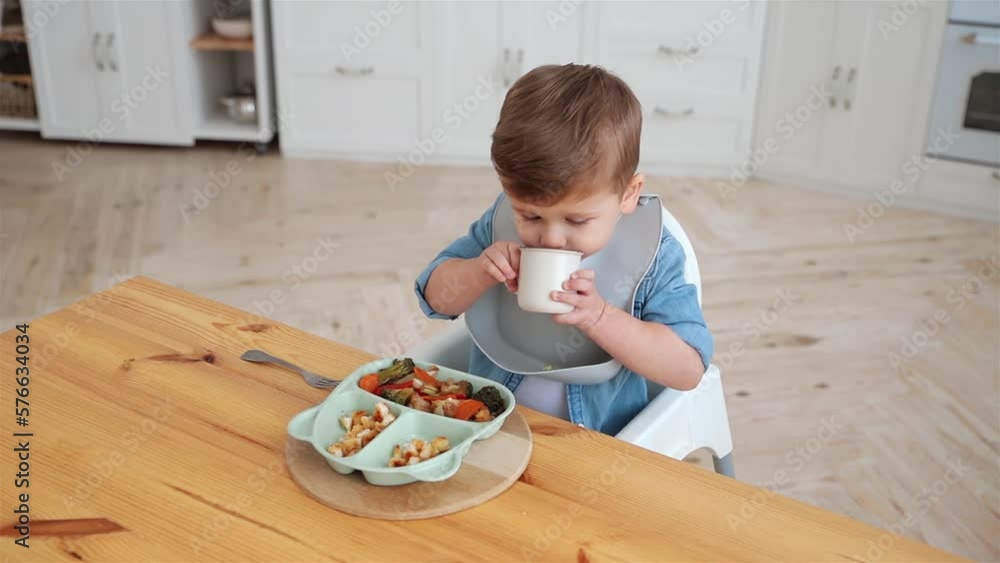 Cute caucasian toddler boy drinking water from a cup on his own using a ...