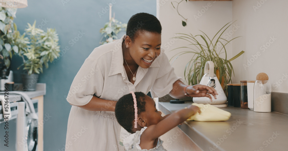 Little girl helping her mother with household chores at home. Happy mom ...