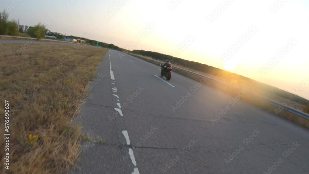 Follow to biker riding on modern sport motorbike on country road at ...