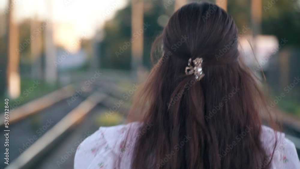 Shooting over shoulder of slim retro woman start walking on railroad ...