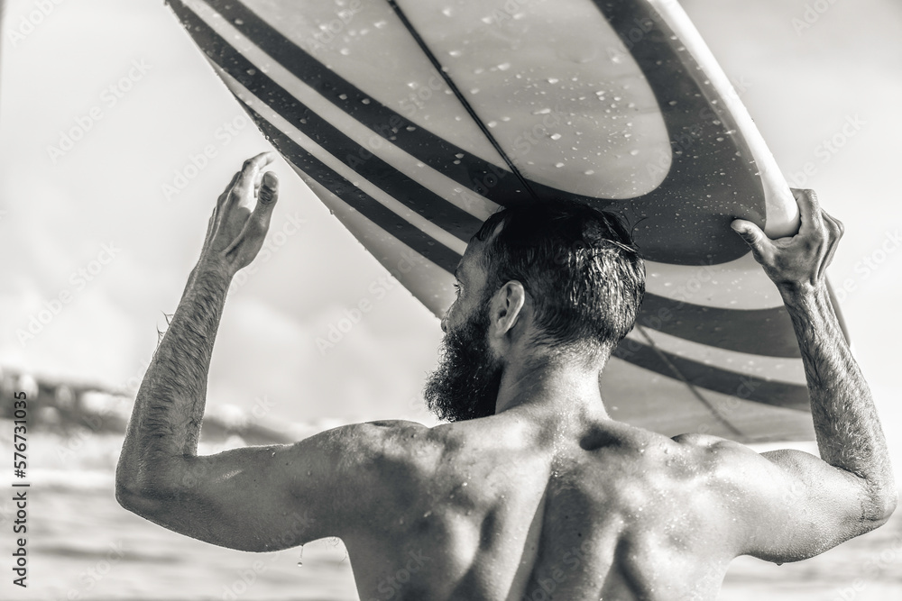 Young hipster man with surfboard on his head greeting friends with a ...
