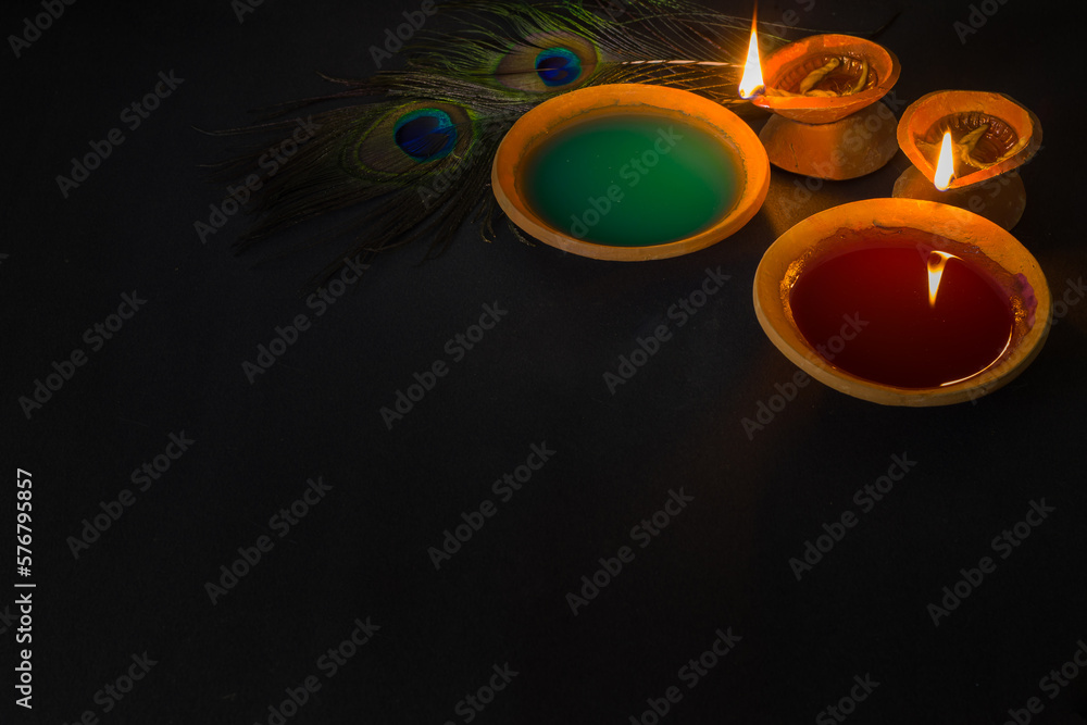 happy holi celebration with colors, clay lamp and peacock feather ...