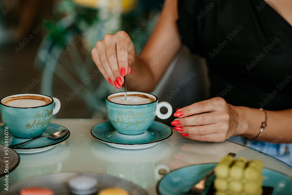 woman details hands drinking coffee eating cakes and macaroons popsi ...