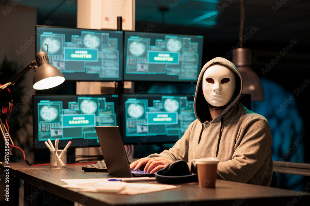 Hacker wearing mask and hood to hack computer system, breaking into company servers to steal big ...