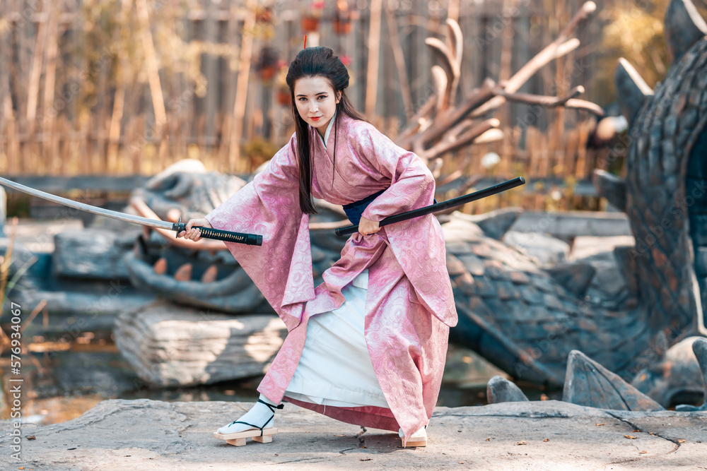 Japanese geisha in a traditional kimano with a fan and armed with a ...