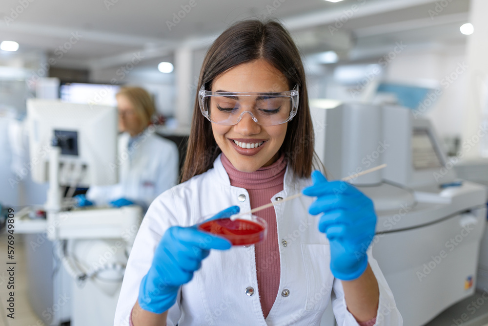 Petri dish in hand of young scientist near microscope in laboratory ...