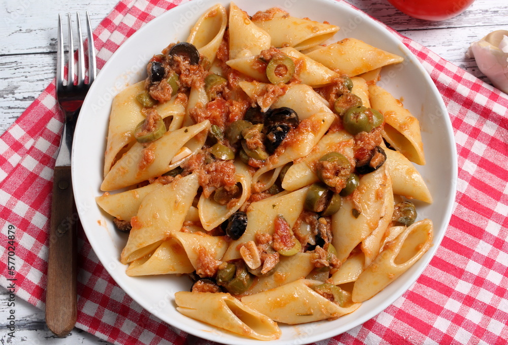 Tasty dish of Italian pasta topped with tuna sauce, black olives, green ...