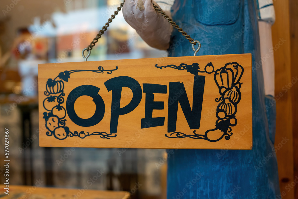 Brown wooden sign hanging in front of a glass entrance door with the ...