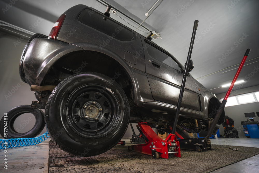 Car servise lifting car and changing wheels using trolley jack. A ...