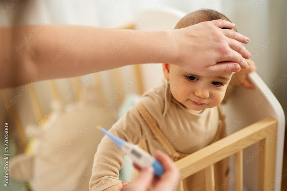 Mother checking body temperature of her baby boy with a thermometer ...