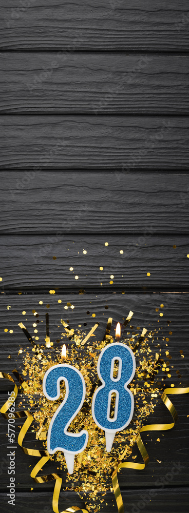 Number 28 blue celebration candle and gold confetti on dark wooden ...