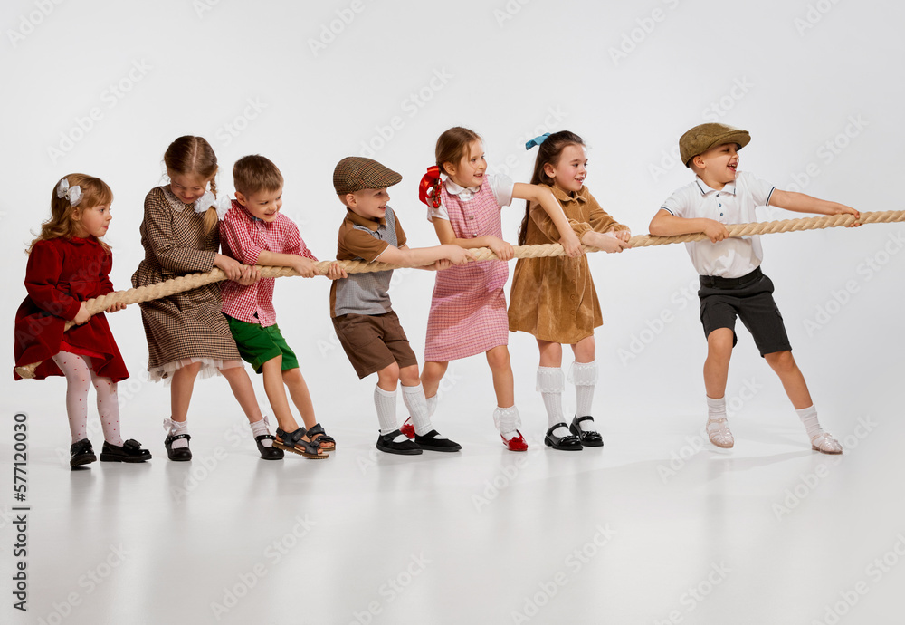 Group of little children, boys and girls playing together, pulling rope ...
