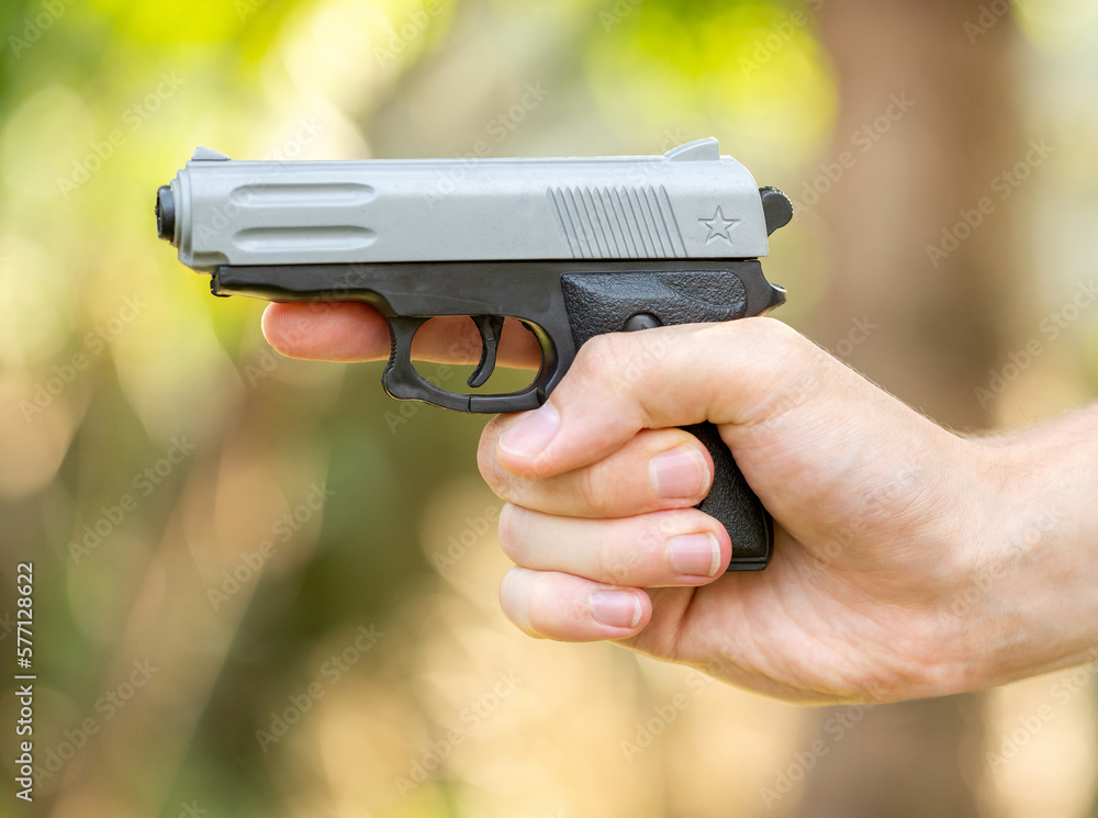 Hand holding a simple small generic plastic toy gun, pistol, fake ...