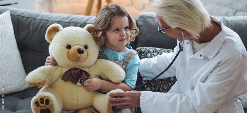 Kind female senior paediatrician doctor visiting his patient at home ...