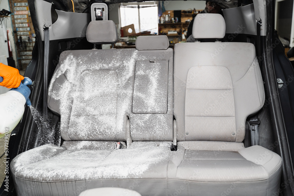 Foto de Spraying detergent on textile seats in car interior for dry ...