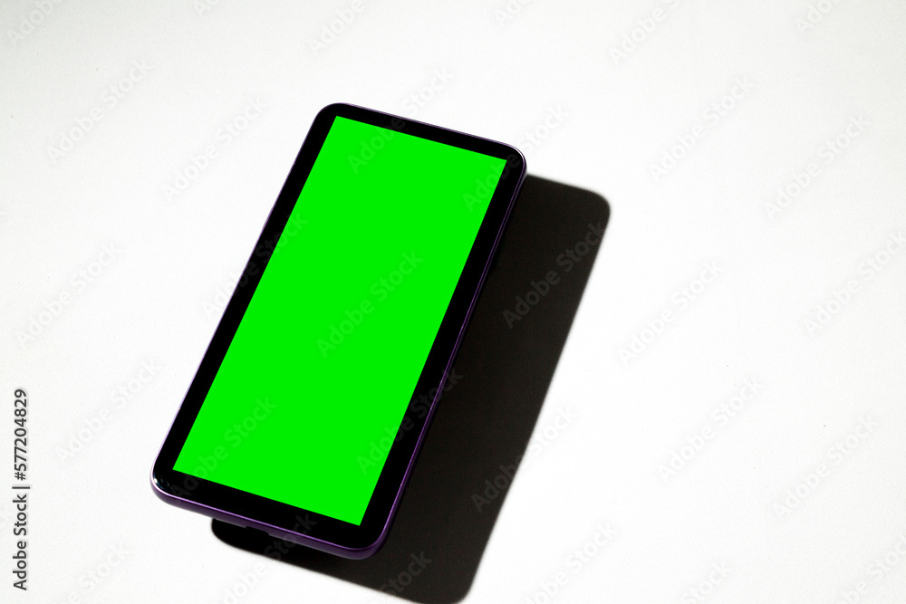 Mobile phone with green screen on top of gray table. smartphone concept ...