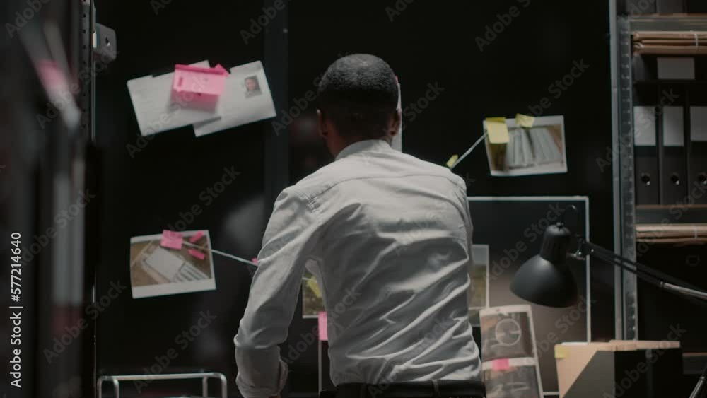 Professional police officer hanging clues on wall map to conduct ...