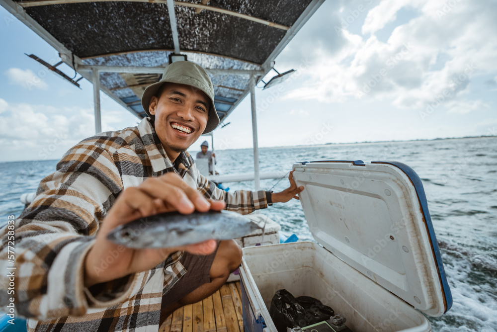 smiling angler showing fish for sea fishing in a small fishing boat ...