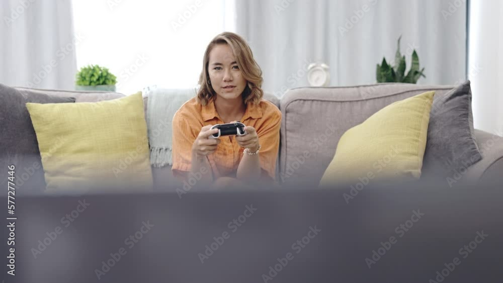 Asian woman, gaming controller and sofa in home living, happy and ...