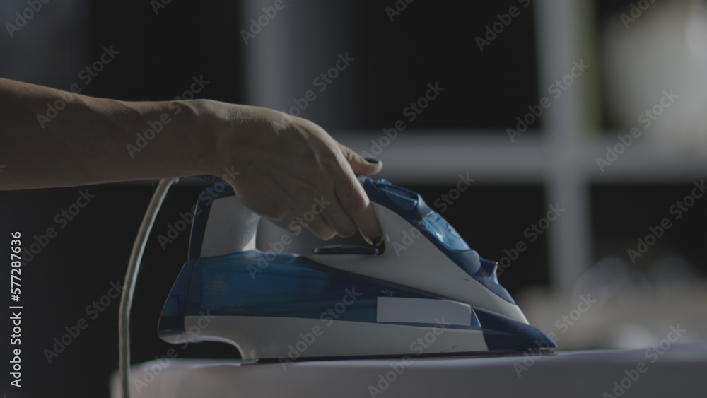 Selective focus of female hand irons white clothes with steam iron on ...