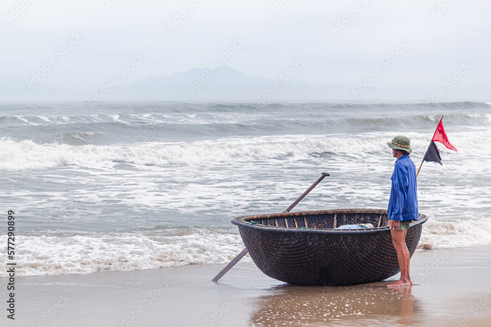 Pêcheur et sa barque traditionnelle en coquille qui attend devant la ...
