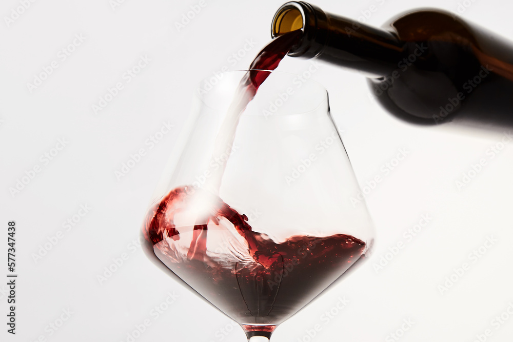 Red wine pouring into tilted wineglass from bottle. Stock Photo | Adobe ...