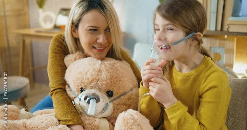 Cheerful little girl having fun while using nebulizer and inhaler for ...