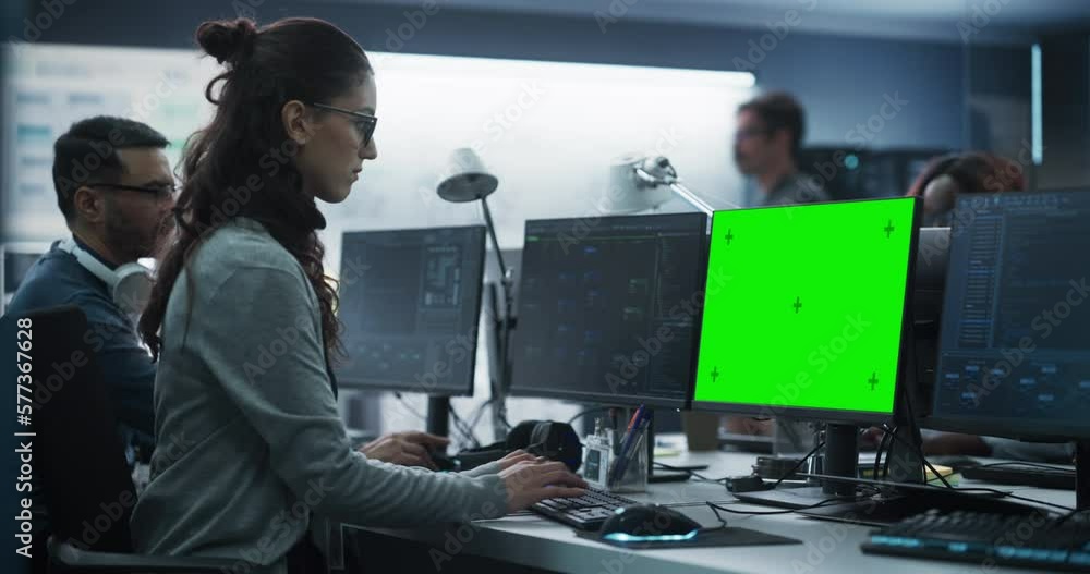 Female Software Developer Working on a Desktop Computer with Green Screen Mock Up Display. Busy ...