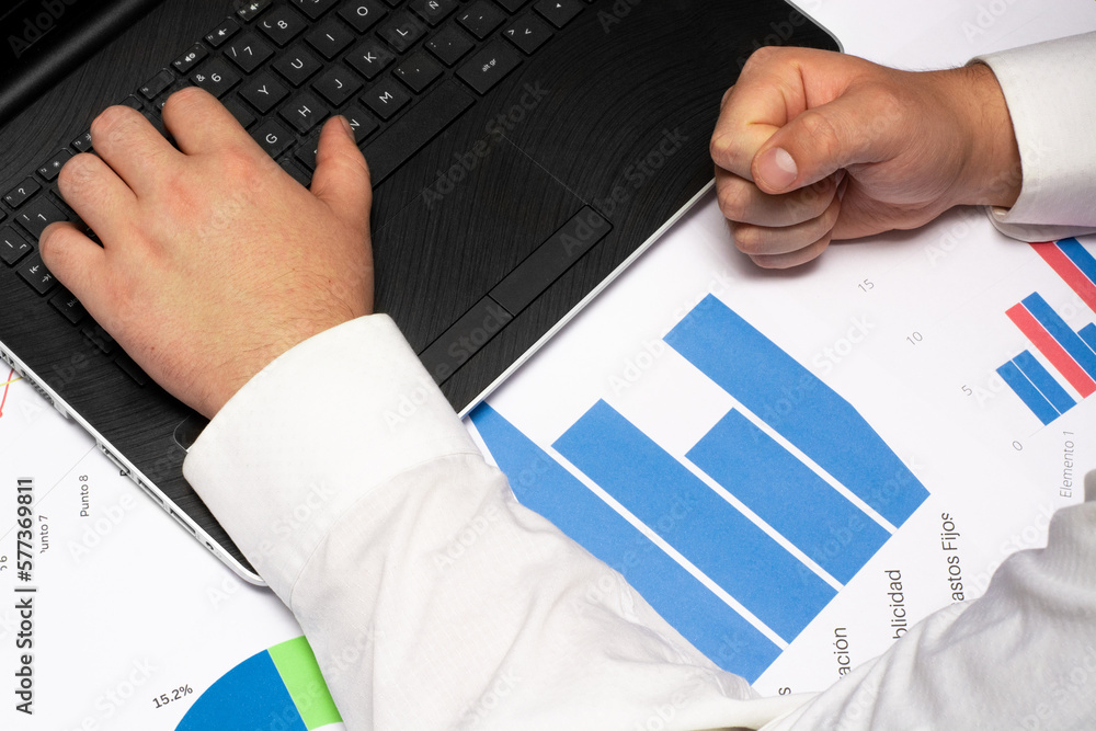 man writing with one hand on a notebook and the other bent on a table ...