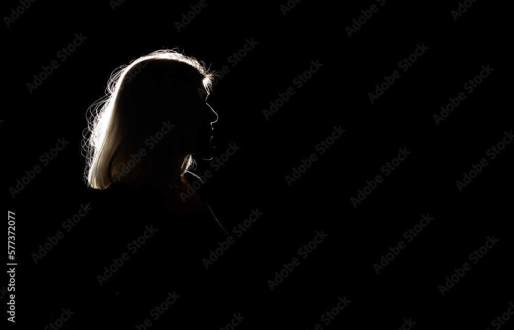 Woman in a dark room in front of a bright light in a head portrait ...